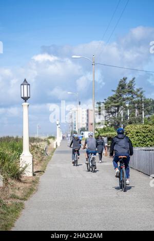 Group of amateur cyclists ride bicycles along the city sidewalk ...
