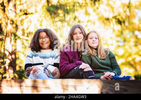 Three pretty tween girls laughing together outdoors in fall colors ...