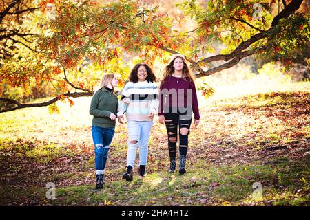 Three pretty tween girls laughing together outdoors in fall colors ...
