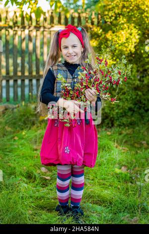 A branch of hawthorn in the hands of a cute girl in the garden. Autumn ...