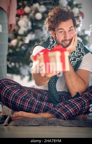 Handsome man with Christmas tree on blue background Stock Photo - Alamy