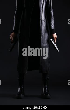 Woman with guns dressed in matrix style on dark background Stock Photo ...