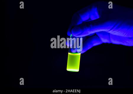 A scientist holding chemistry photochemical reaction green glass vials ...