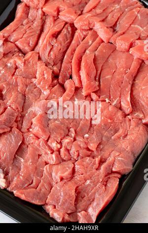 raw vertically sliced beef on a white wooden background Stock Photo - Alamy