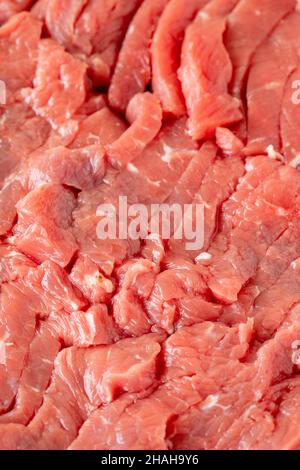 raw vertically sliced beef on a white wooden background Stock Photo - Alamy