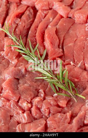 raw vertically sliced beef on a white wooden background Stock Photo - Alamy
