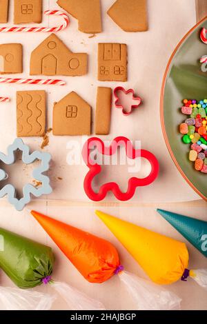 Woman is decorating gingerbread cookies house with white frosting icing ...