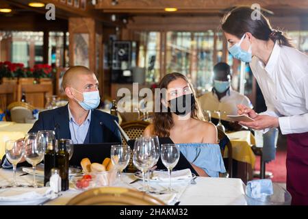 Positive young couple making order at restaurant Stock Photo - Alamy