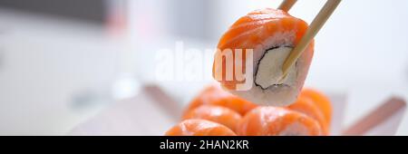 Hand with disposable chopsticks holds sake nigiri sushi with salmon fish Stock Photo - Alamy