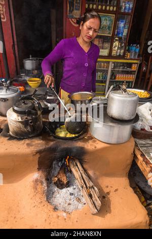 A woman cooks on a chulo or traditional outdoor wood-burning stove made ...