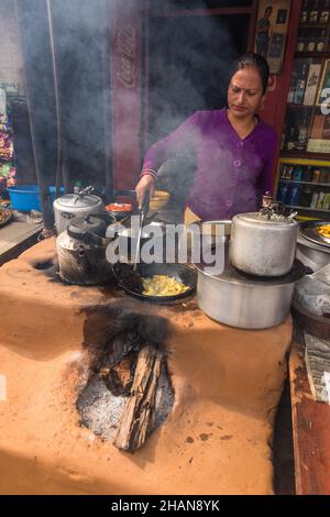 A woman cooks on a chulo or traditional outdoor wood-burning stove made ...
