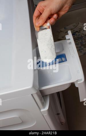 hand pouring washing powder into detergent compartment of an old ...