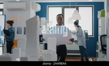 Portrait of engineer analyzing blueprints plan and building model to ...