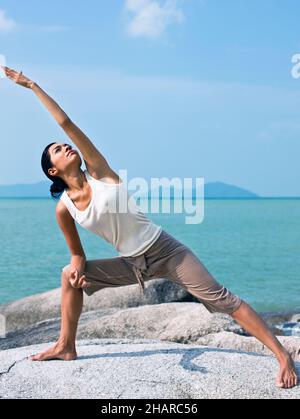 Woman practices yoga at the beach on sunset Stock Photo - Alamy