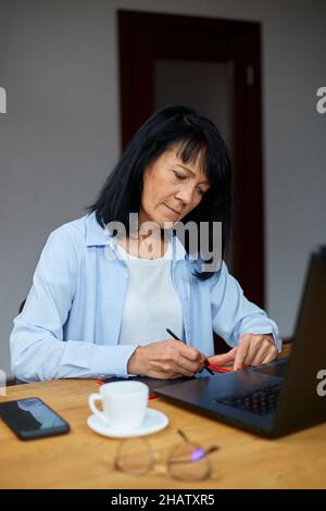 Senior woman designer using graphics tablet and stylus, working at ...