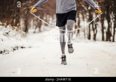 Legs jumping the rope on snowy path at winter. Winter sport, cardio ...