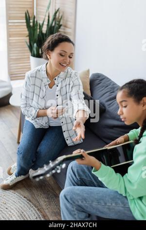 Kid pointing at smartphone near mom and soft toy on bed in clinic,stock ...