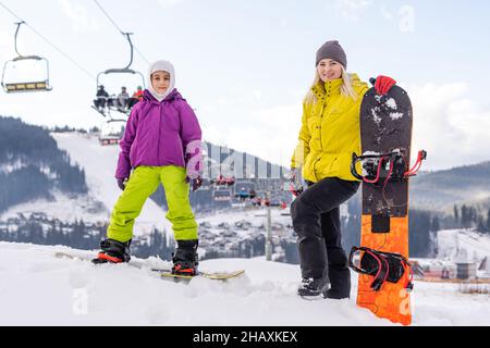 mother and daughter with snowboards in a mountain resort Stock Photo ...