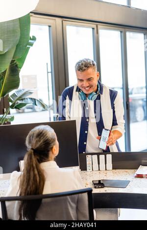 Cheerful male worker with headphones surfing modern netbook while ...
