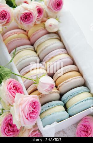 Tasty macaroons and roses in box on light background Stock Photo - Alamy