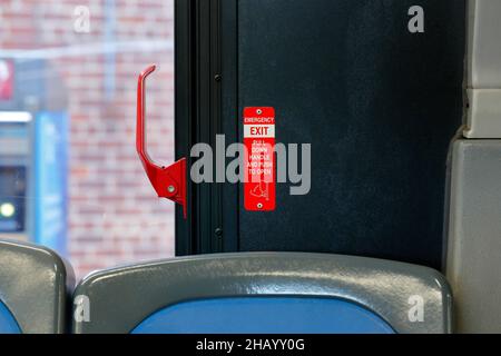 Red emergency exit handle on window on moving public transportation bus ...