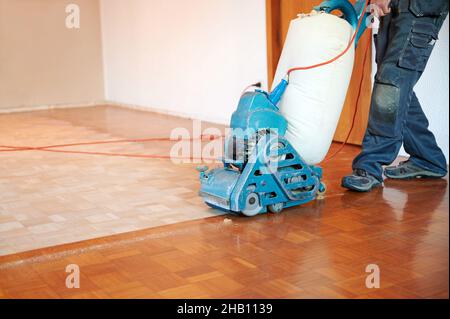 Worker polishing parquet floor with grinding machine Stock Photo - Alamy