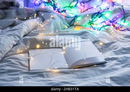 Opened book with blank pages, beautiful decor and glowing lights on ...