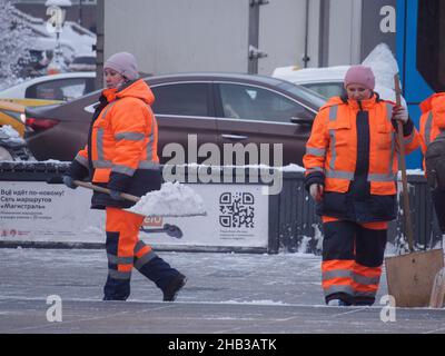 Workers use shovels to clear a snow-covered side street in downtown ...