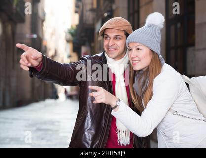 Adult tourists in hats and scarfs pointing finger on historical object ...