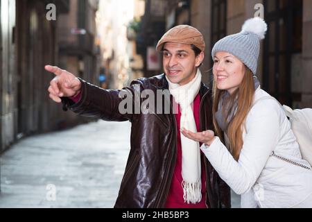 Adult tourists in hats and scarfs pointing finger on historical object ...