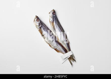 Two salted air-dried sabrefish with paper labels on tails isolated on ...