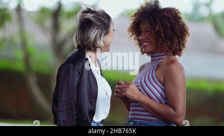 Two diverse friends talking outside at park. people conversation Stock ...