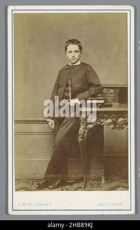 Portrait of an unknown boy, standing next to a table with a dog ...