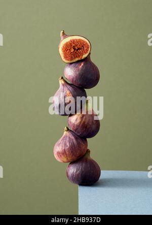 Fresh figs balancing on the edge of a table, with green background ...