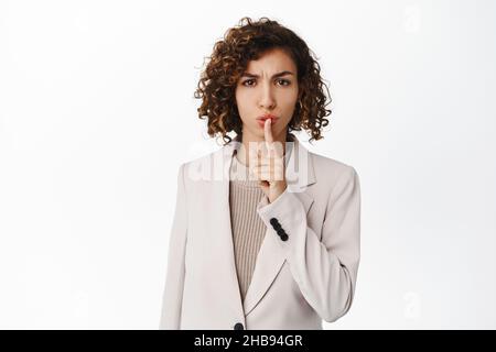 Female office worker making shush gesture Stock Photo - Alamy