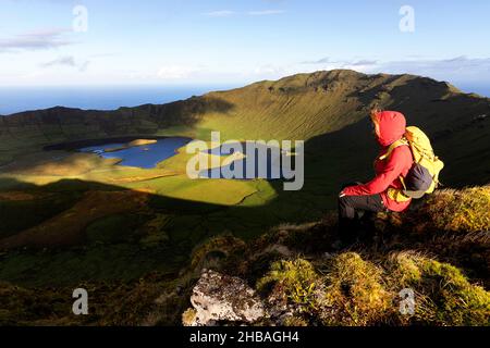 Woman with yellow backpack enjoying the sunrise view to Caldeirao ...