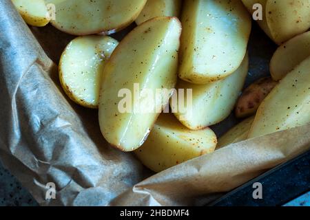 fresh raw potatoes wedges mixed with oil and spices ready for baking ...