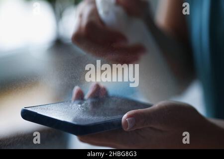 Spray antiseptic on mobile phone screen, antibacterial and disinfecting ...