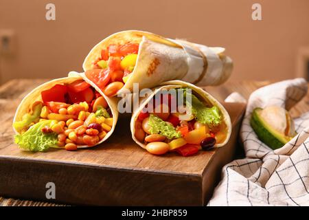 Board of tasty Mexican burritos with vegetables on table, closeup Stock ...