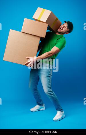 Delivery man with huge pile of boxes against blue background Stock ...