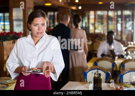 Portrait of upset waitress disappointed in small tip from guests at ...