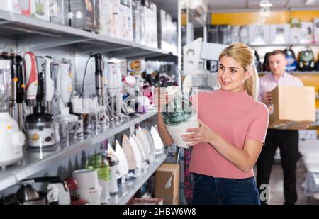 Young woman is choosing blender for his kitchen in appliances store ...
