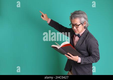 The senior Asian teacher standing on the green background Stock Photo ...