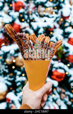 Churros waffles in hand on the street. Churros street food dessert made ...