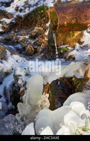 Spring water falling from a pipe in winter Stock Photo - Alamy