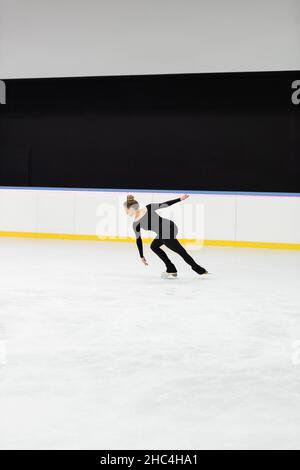 full length of professional figure skater in black bodysuit skating ...