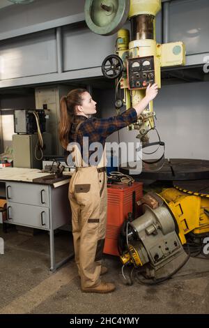 Side view of welder in overalls sitting near keyboard and welding ...