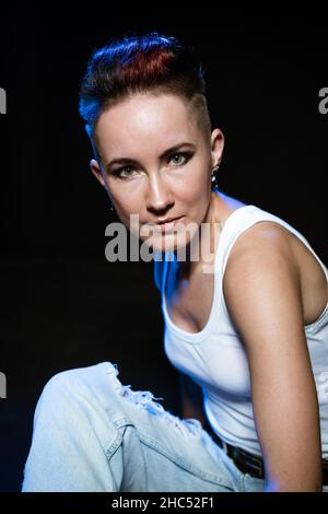 portrait of pretty woman with neon makeup looking away in blue light on ...