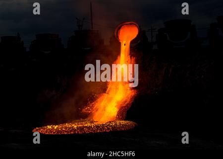 Colorful stream of molten metal at a steel mill. Blast furnace slag at ...