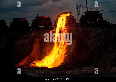 Colorful stream of molten metal at a steel mill. Blast furnace slag at ...